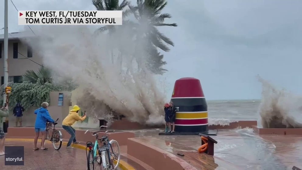 People pose for photos as large waves from Hurricane Ian pound Key West ...